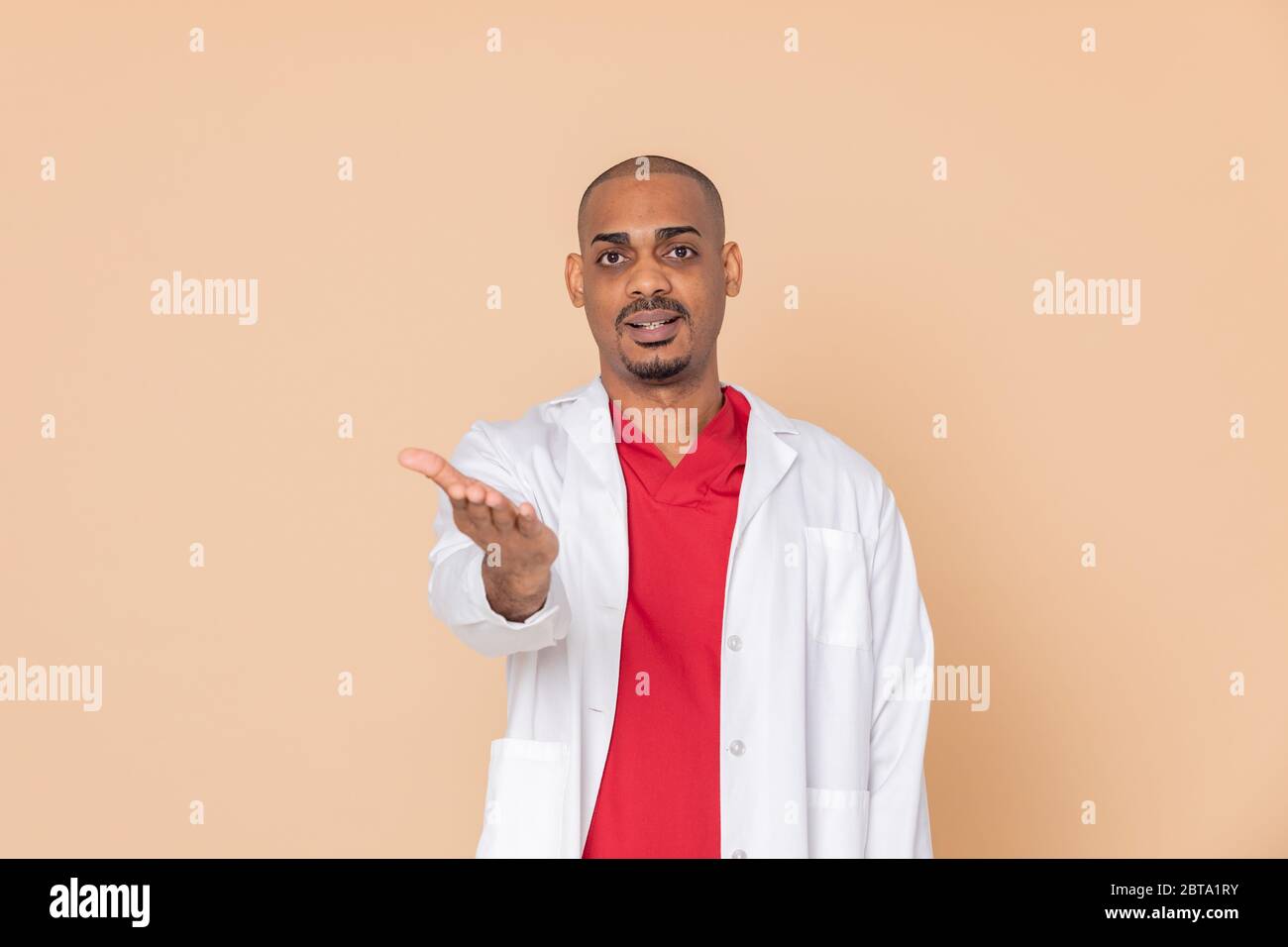 Friendly doctor wearing red uniform on a orange background Stock Photo ...
