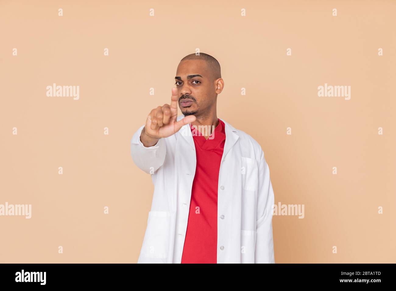 African doctor pointing at camera on a orange background Stock Photo ...
