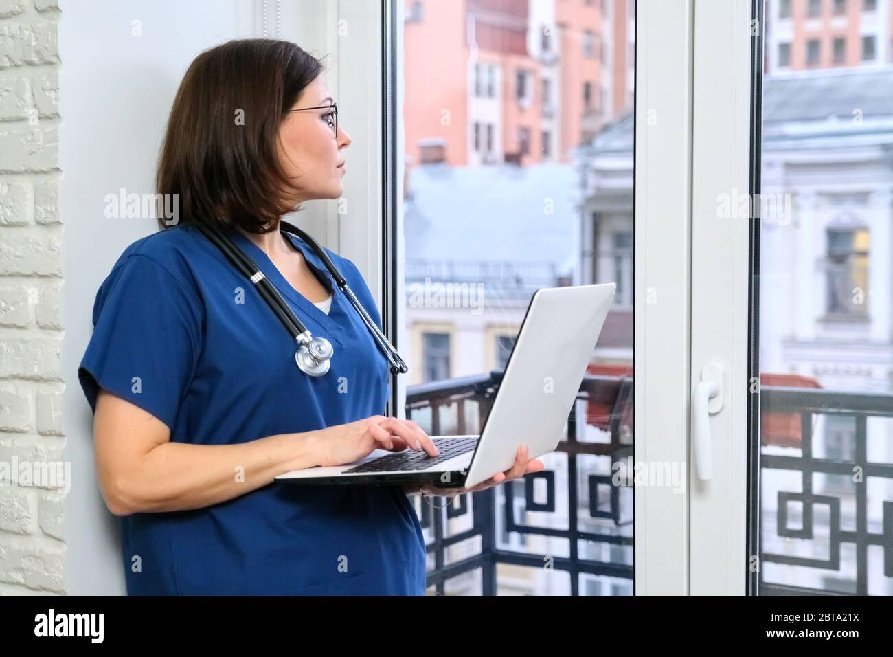 Female nurse using laptop computer, doctor near window in clinic office ...