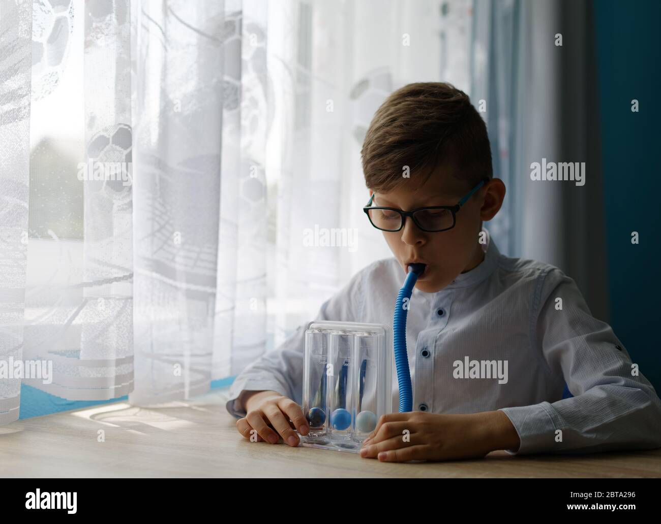 Young caucasian boy deep breathing exercise with spirometer ...