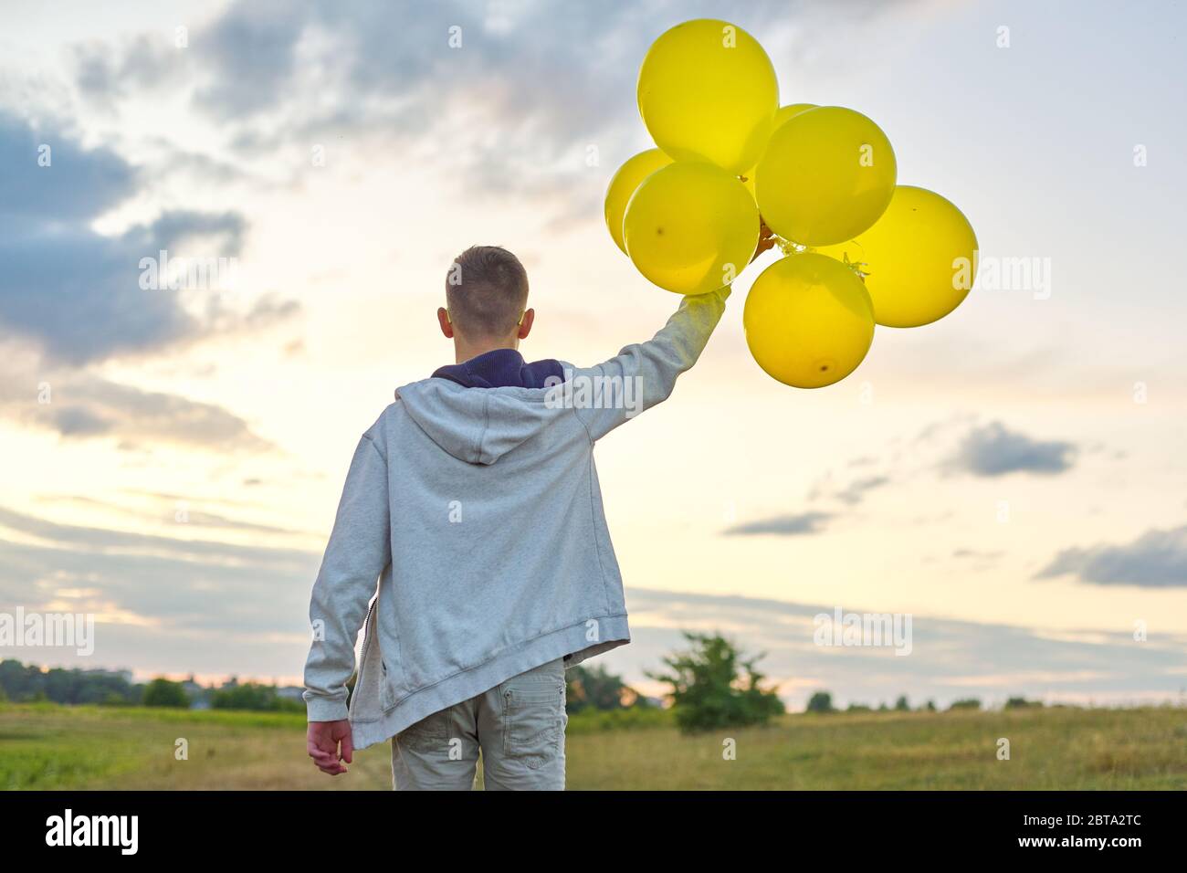Teen boy running with balloons, view back Stock Photo - Alamy