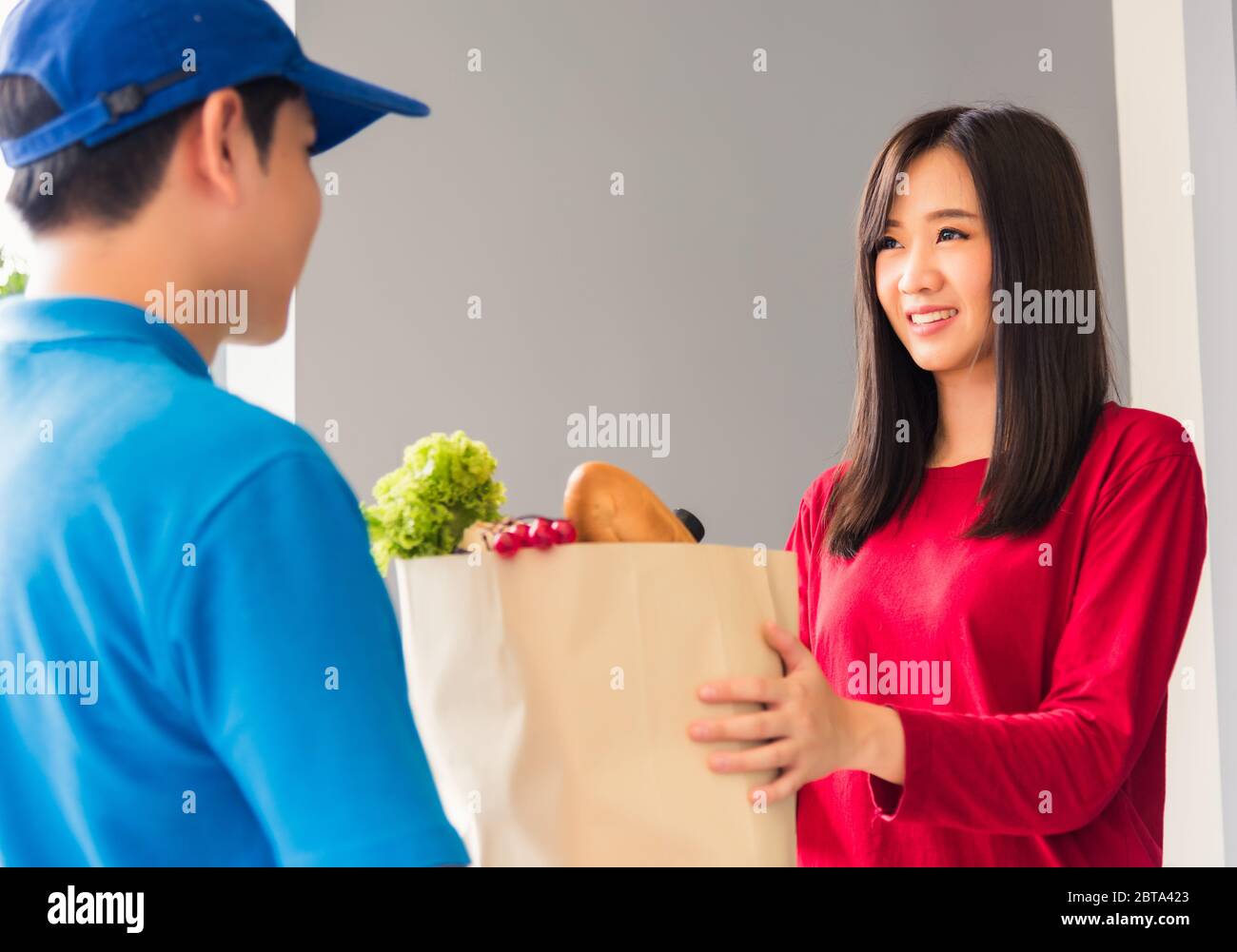 Asian young delivery man in uniform making grocery fast service giving ...