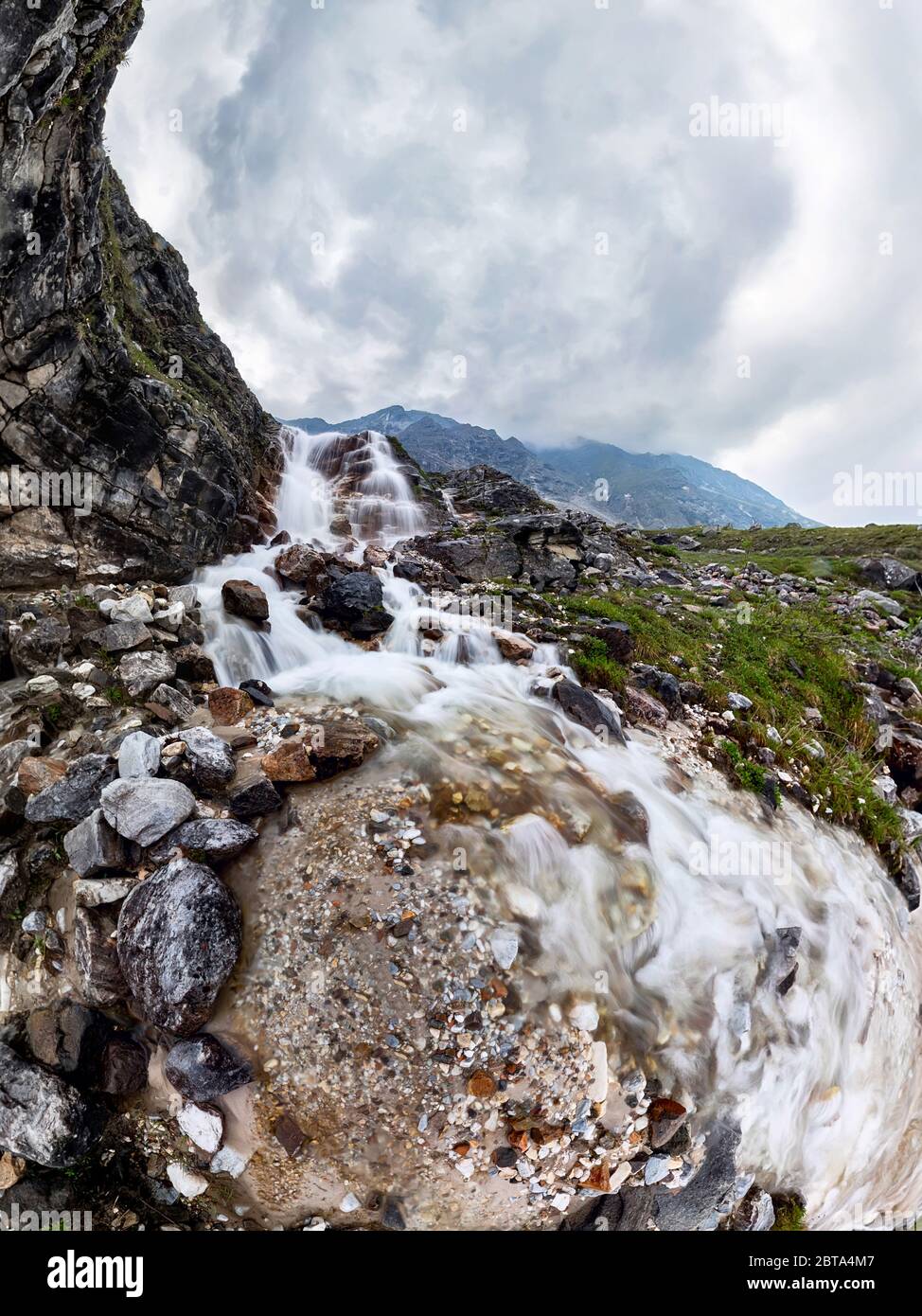 Mountain waterfall stream in misty rainy weather in the valley flowers ...