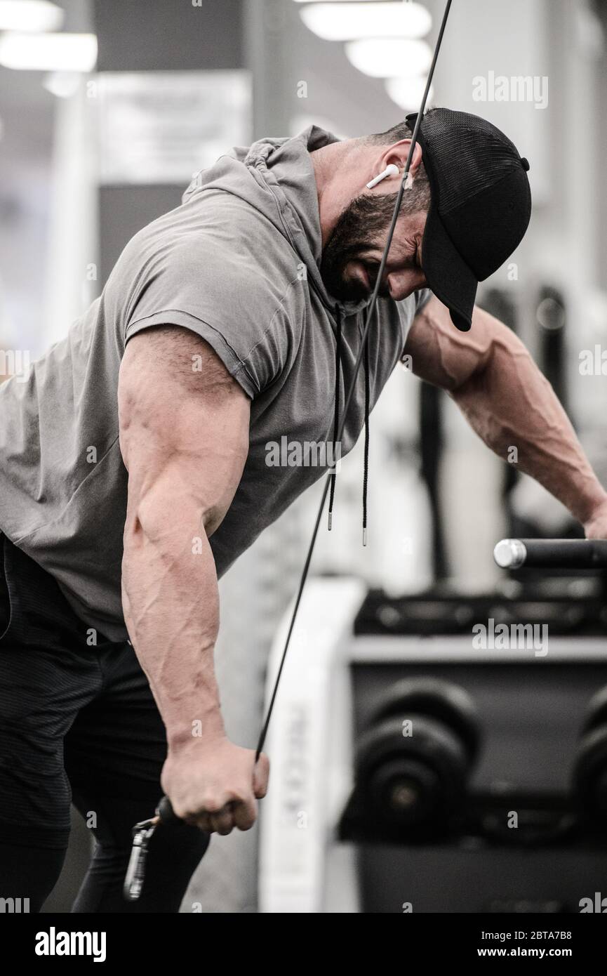 strong young bearded man in cap and sportswear and wireless headphones ...
