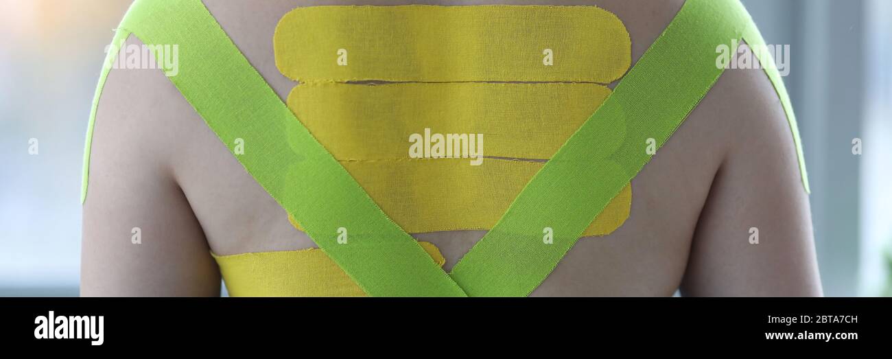 Female wearing kinesio tapes at her back and shoulders at doctor office ...