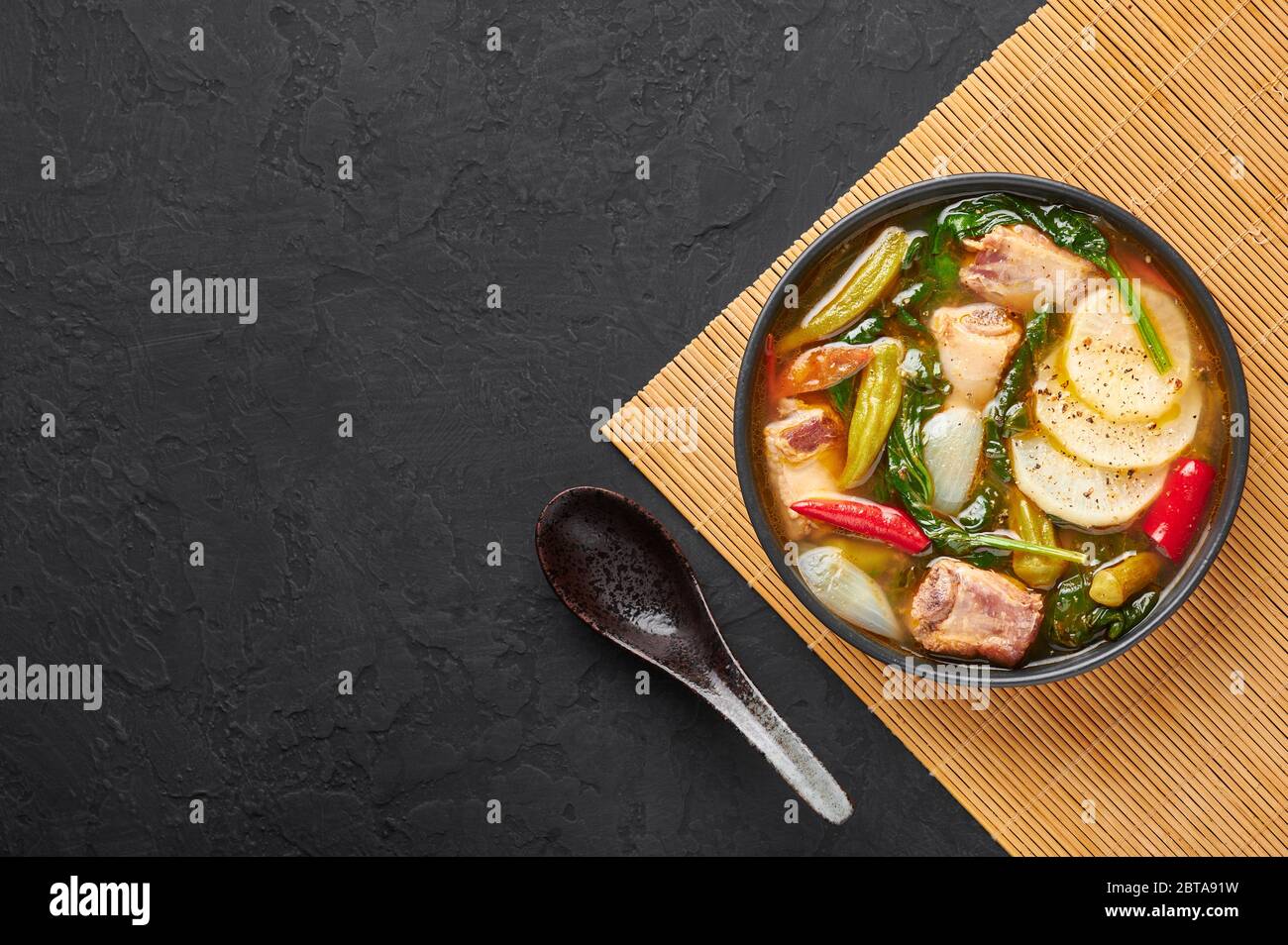 Sinigang na Baboy or Filipino Pork Meat Soup in black bowl on dark ...