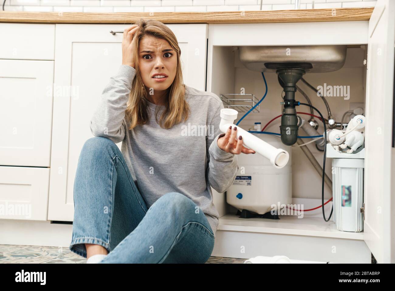 Photo of displeased confused blonde woman with plumbing pipes while ...
