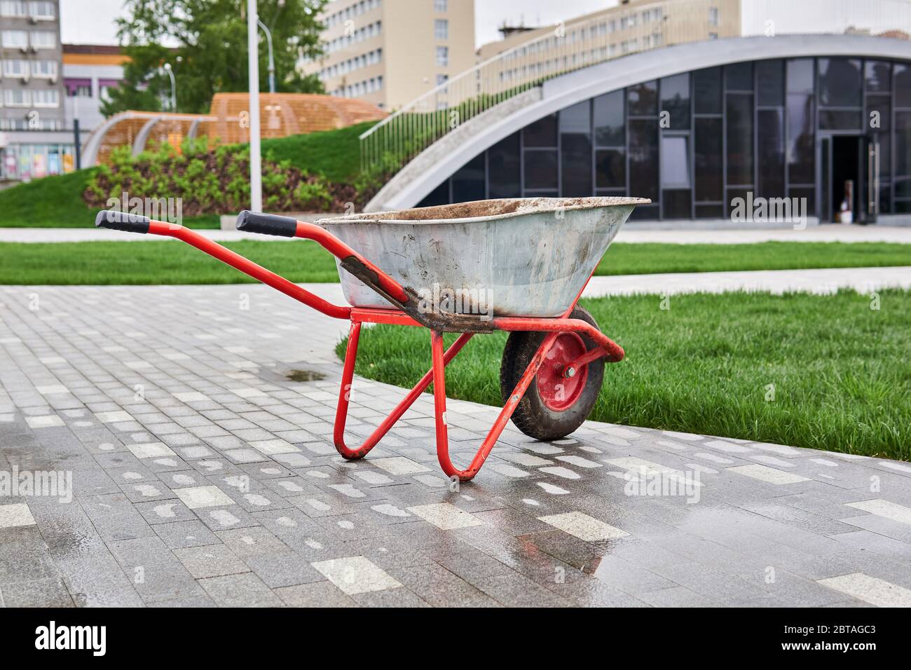 used wheelbarrow on the background of urban landscaping Stock Photo - Alamy