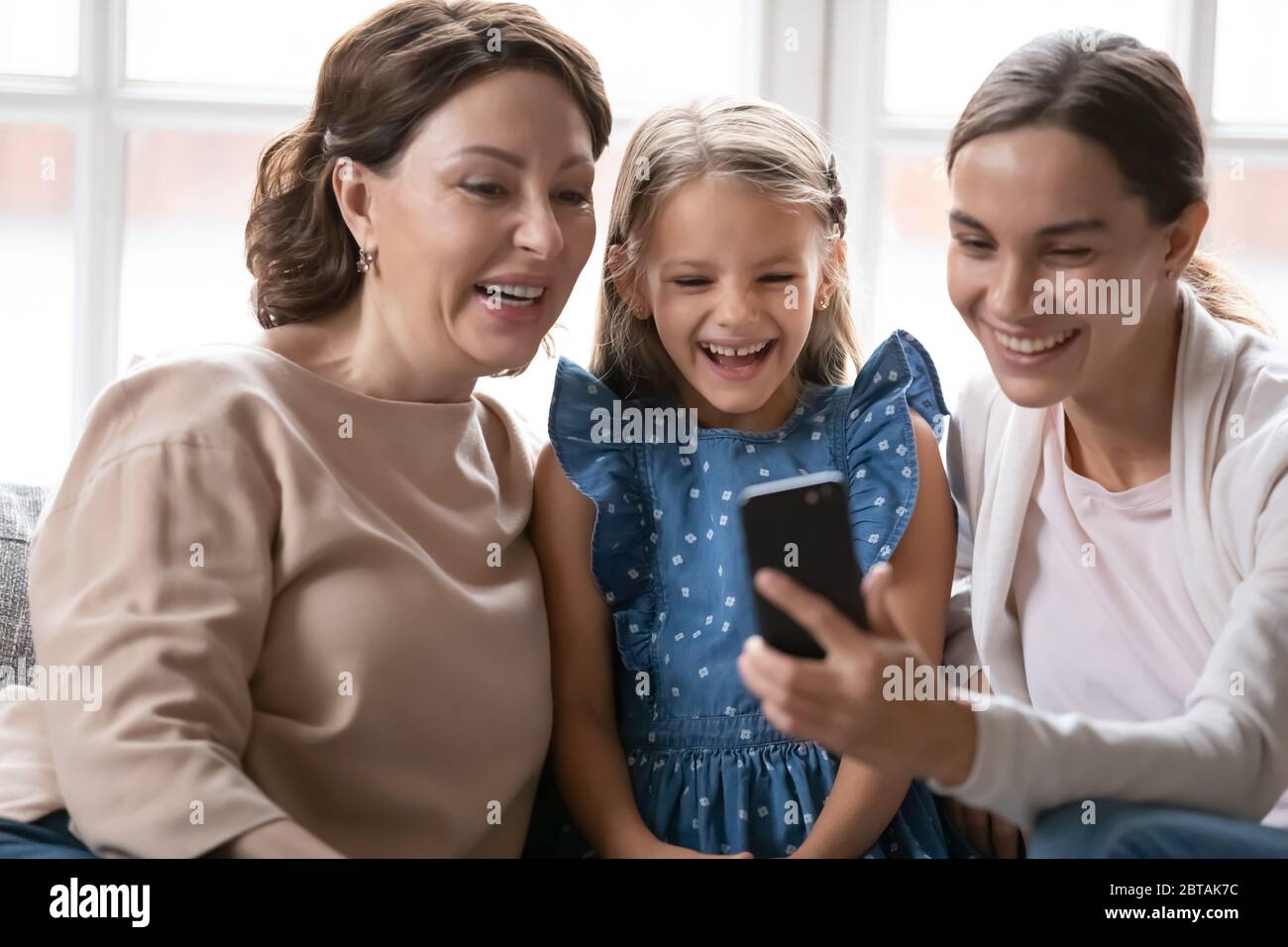 Happy three generations of women have fun using cellphone Stock Photo ...