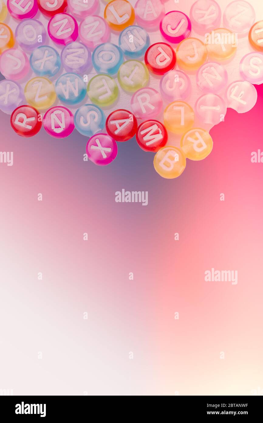 Multi color alphabet letter beads placed randomly on white background ...