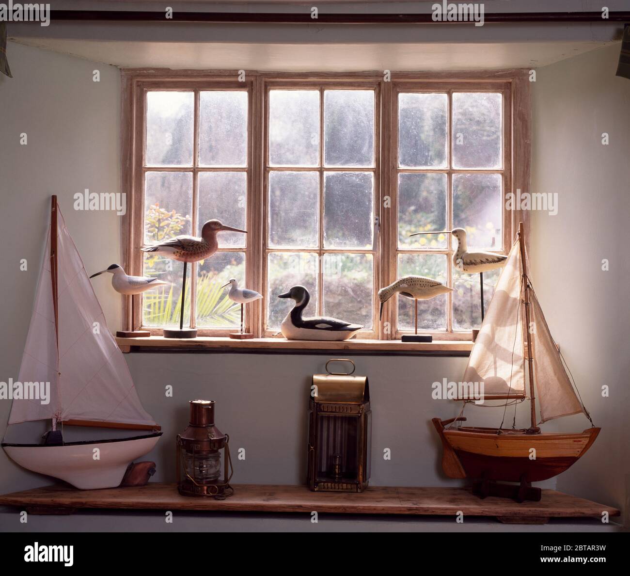Collection of wooden birds on window sill above model yachts Stock ...