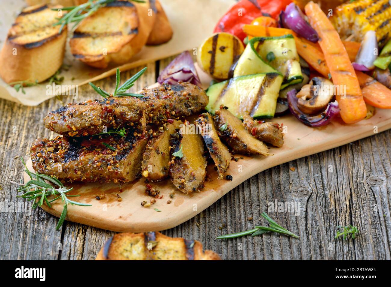Grilled vegan seitan steaks with mixed vegetables and crusty baguette ...