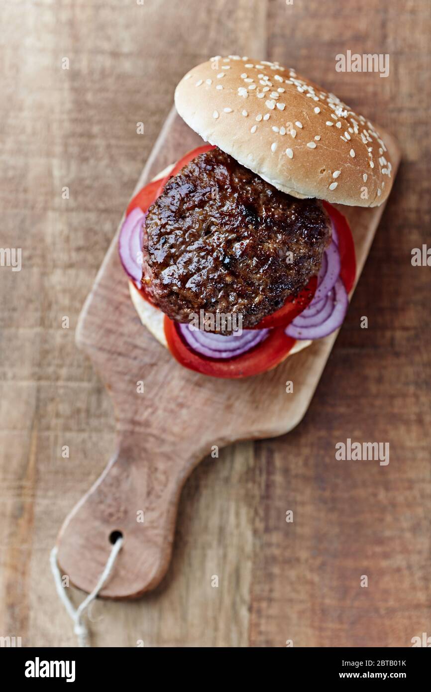 Tasty humburger with tomatoes and red onion. Rustic stone background ...