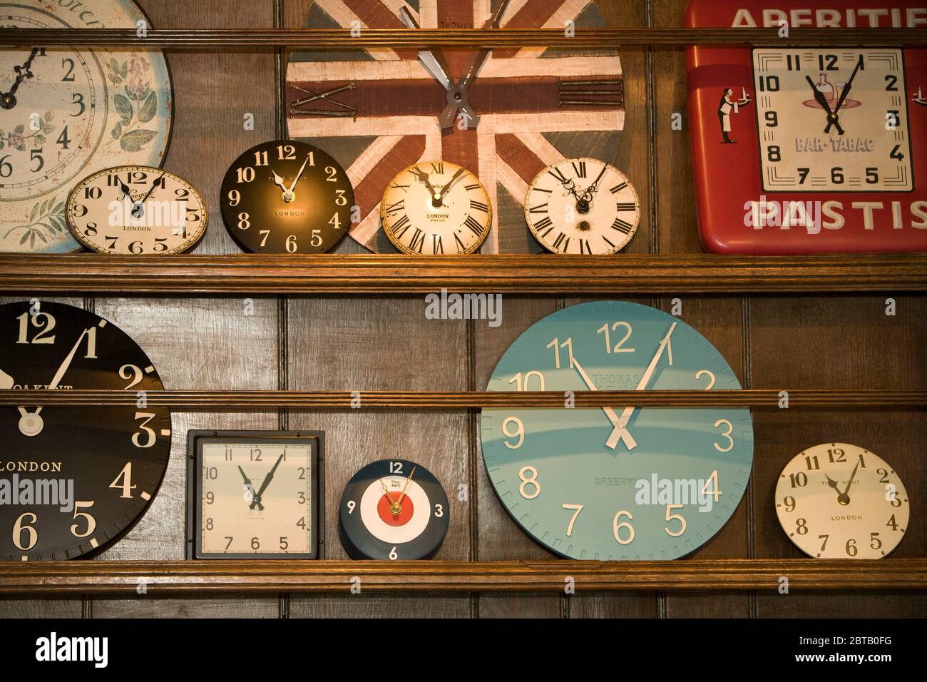 A selection of different retro wall clocks on wooden shelves Stock ...