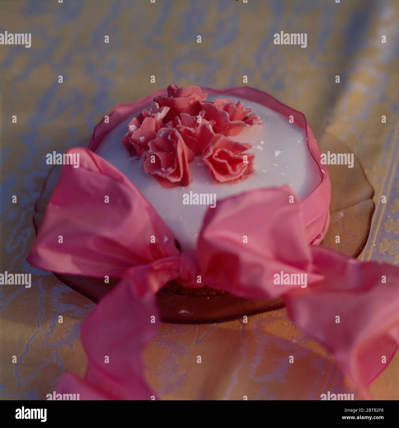 Decoratively iced cake tied with pink ribbon Stock Photo - Alamy