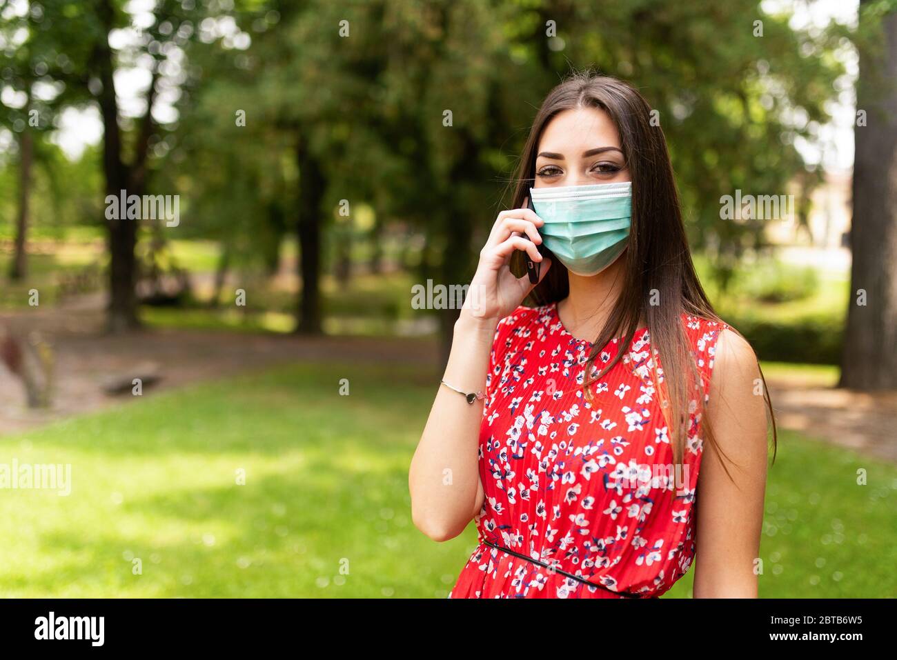 Masked young woman talking on the phone Stock Photo - Alamy