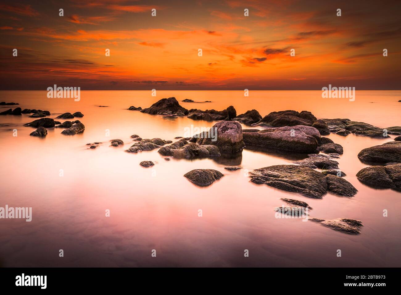 Morning dusk at the shore of Lake Malawi, rocks sticking out the lake ...