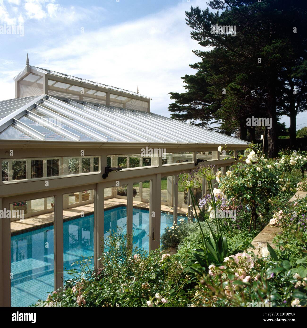 Large conservatory housing a turquoise swimming pool in a country ...