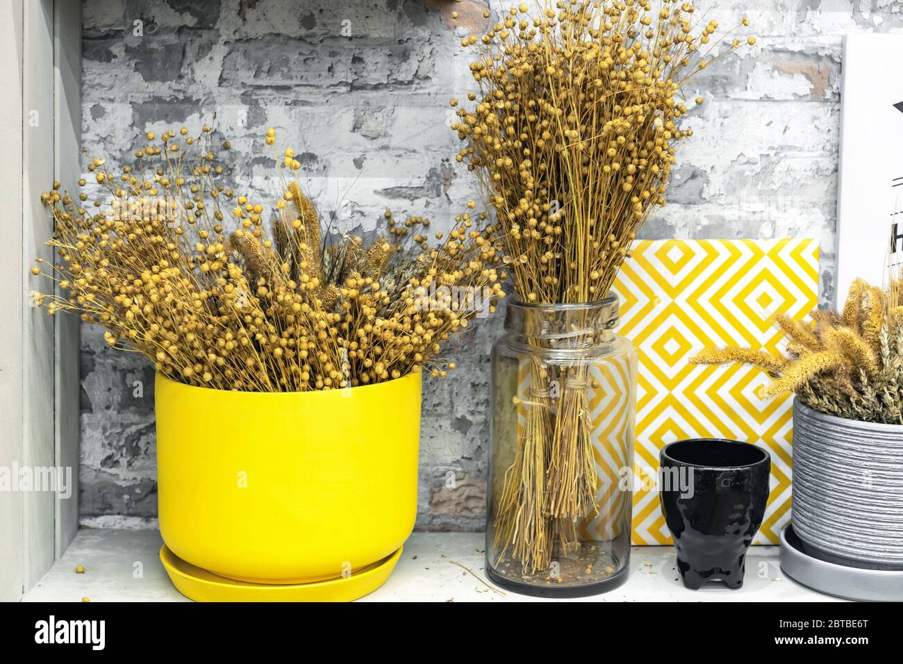 Dry wildflowers in a yellow cache-pot and a transparent bottle. Ekibana ...