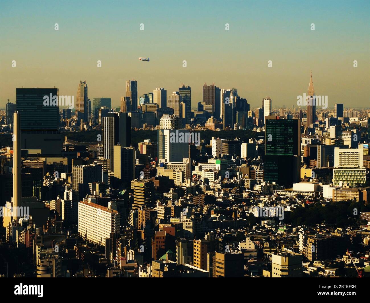Tokyo city view from above with skyscrapers and a zeppelin flying over ...