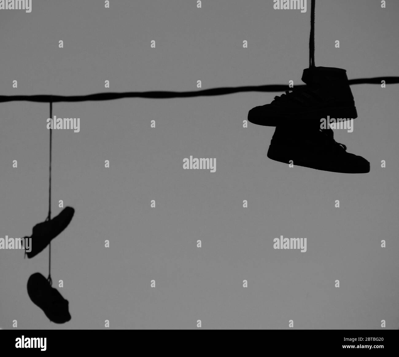The silhouettes of a pair of shoes hanging on a wire in the street ...
