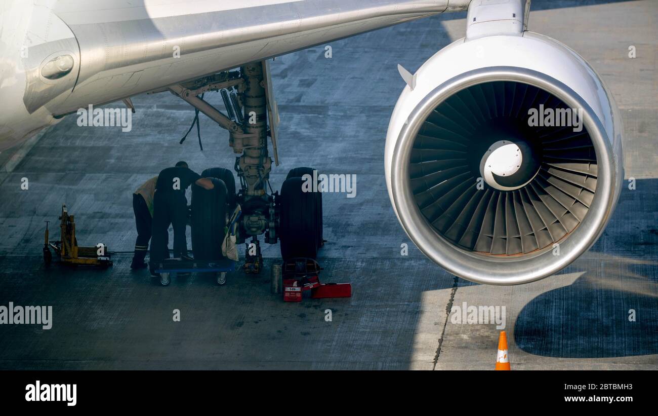 Photo of maintenace ground crew checking airplane chassis before flight ...