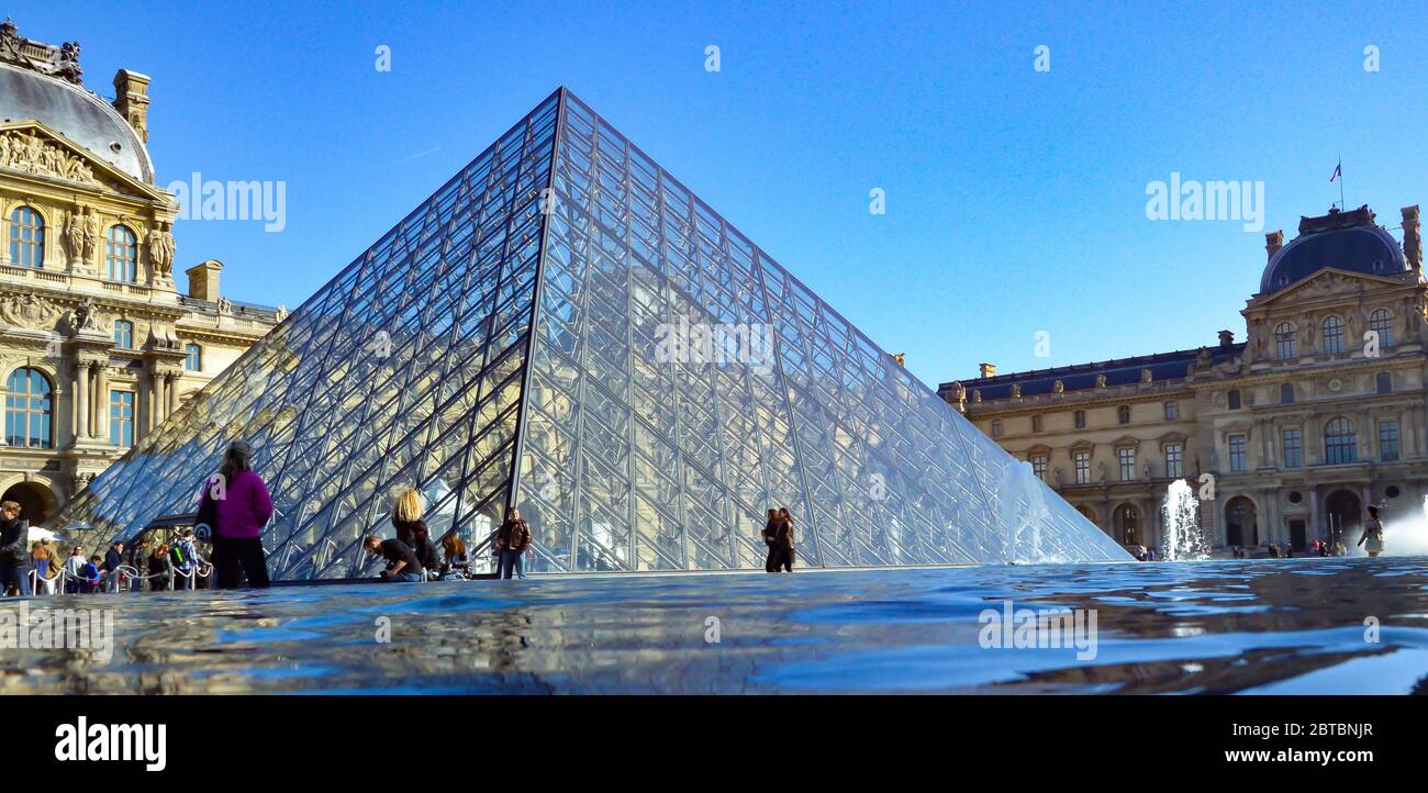 Side view of Louvre Museum with people around in the main square, Paris ...