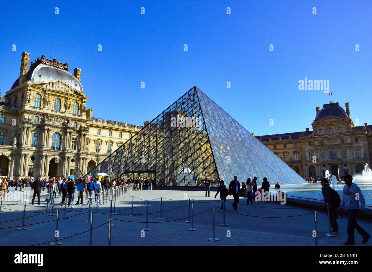 Side view of Louvre Museum with people around in the main square, Paris ...