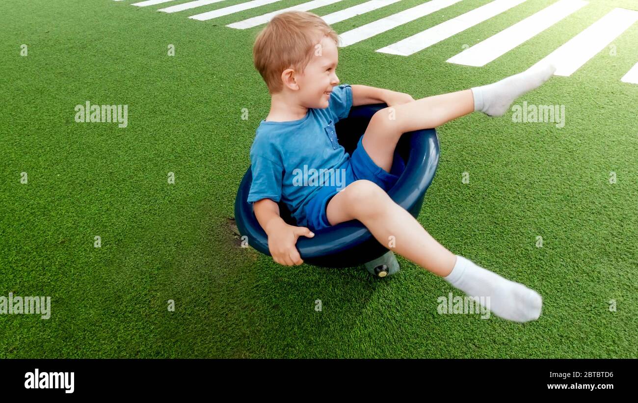 Happy smiling and laughing little boy sitting on rotating chair ...