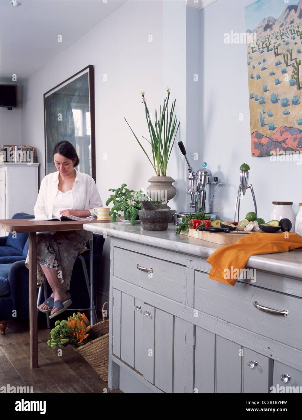 Woman sitting and reading magazine at breakfast bar EDITORIAL USE ONLY ...