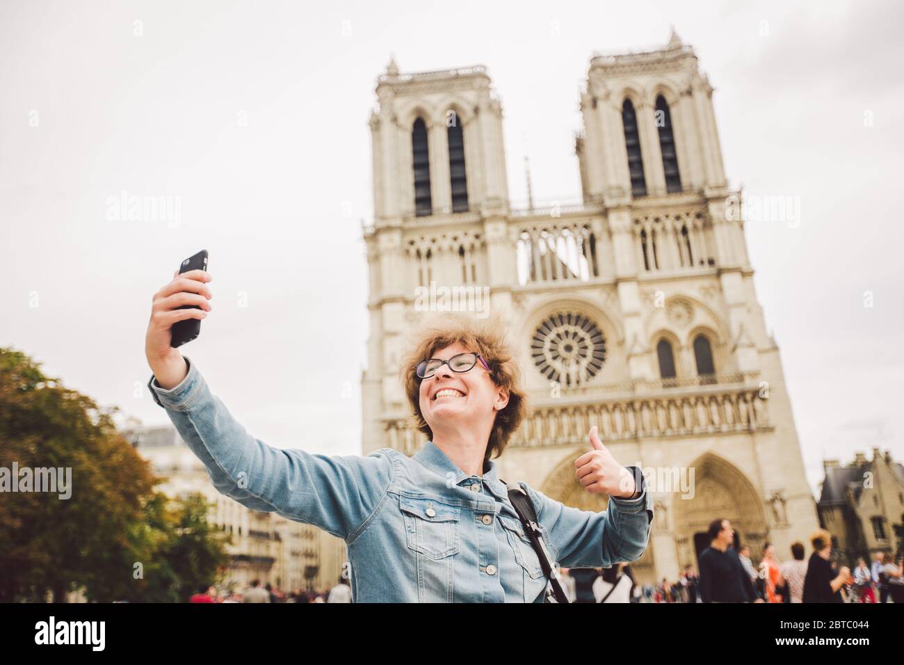 Tourist in Paris making funny selfie near Notre Dame Cathedral ...