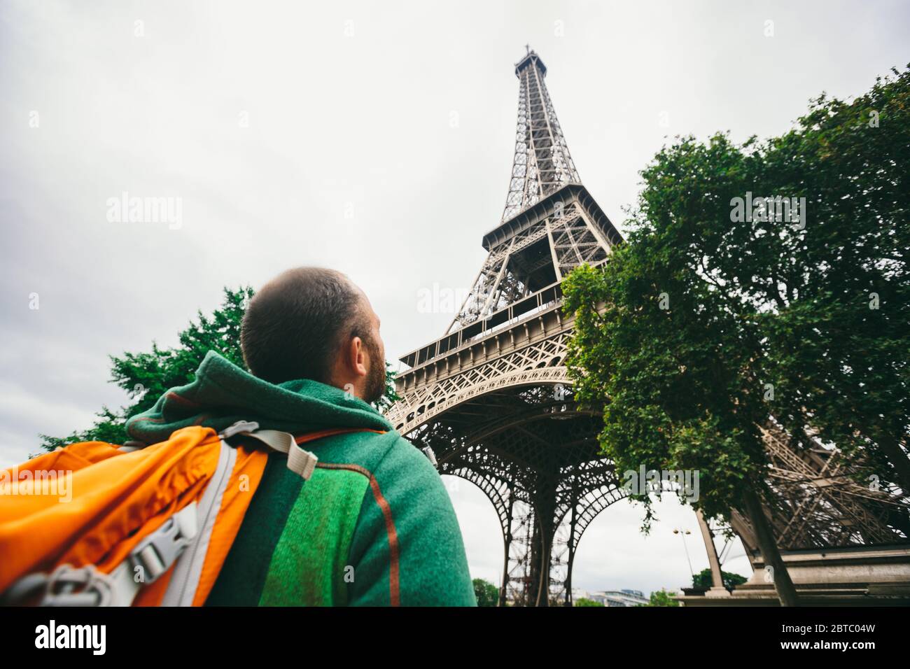 Caucasian male tourist with a backpack looking up and down at the top ...