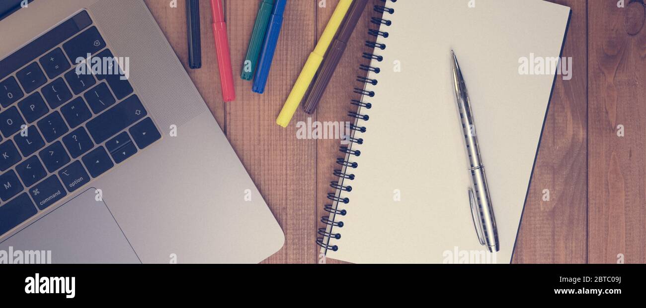Opened blank notebook, laptop and colored felt-tip pens on the desktop ...