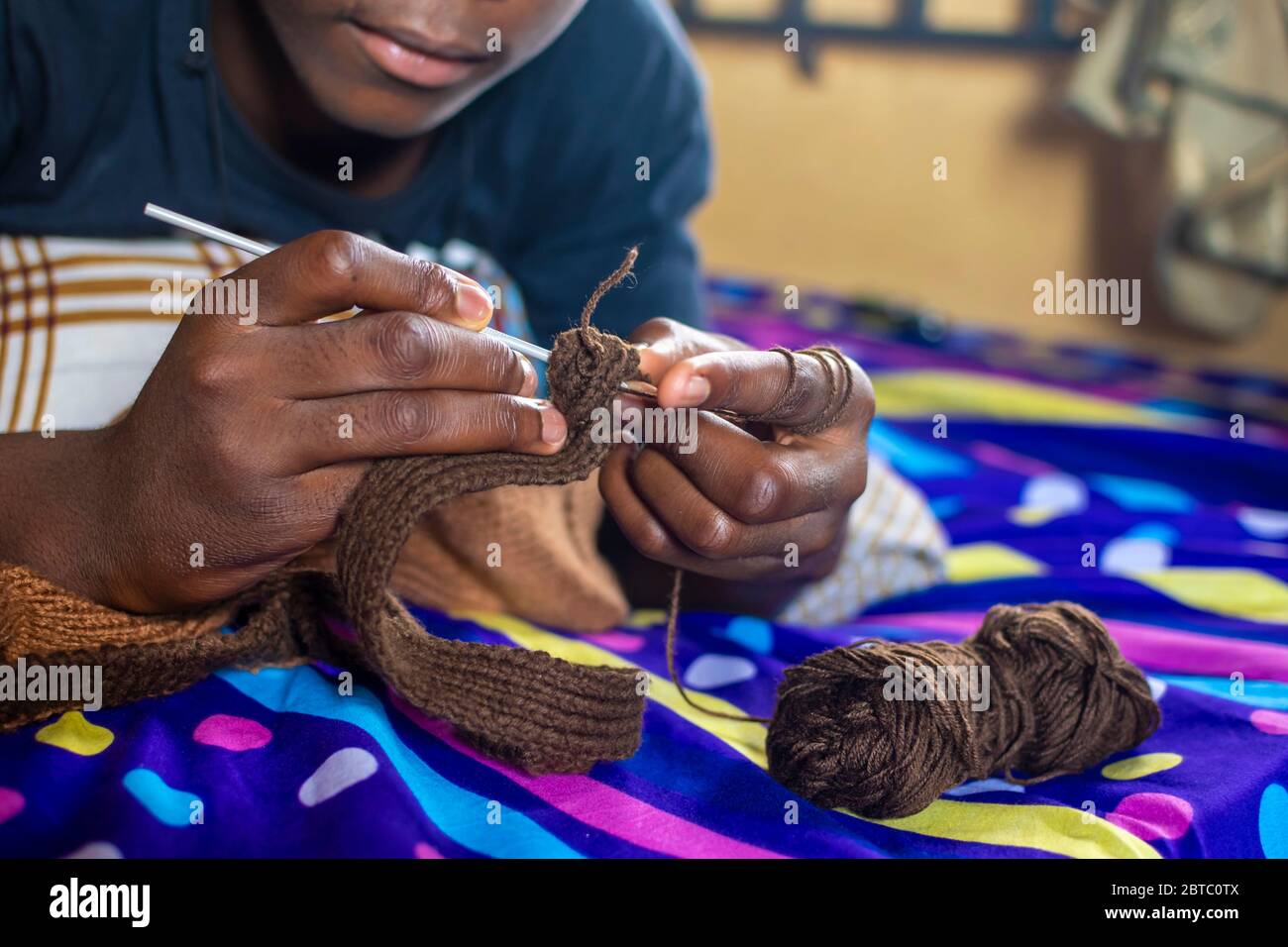 crafty young african boy knitting Stock Photo - Alamy