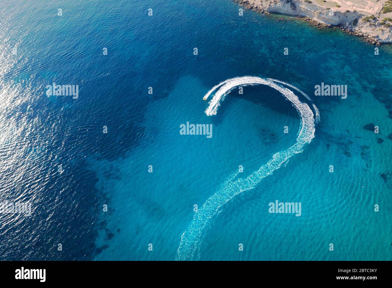 Jet ski rides in bay leaving white trail of foam on blue smooth sea ...