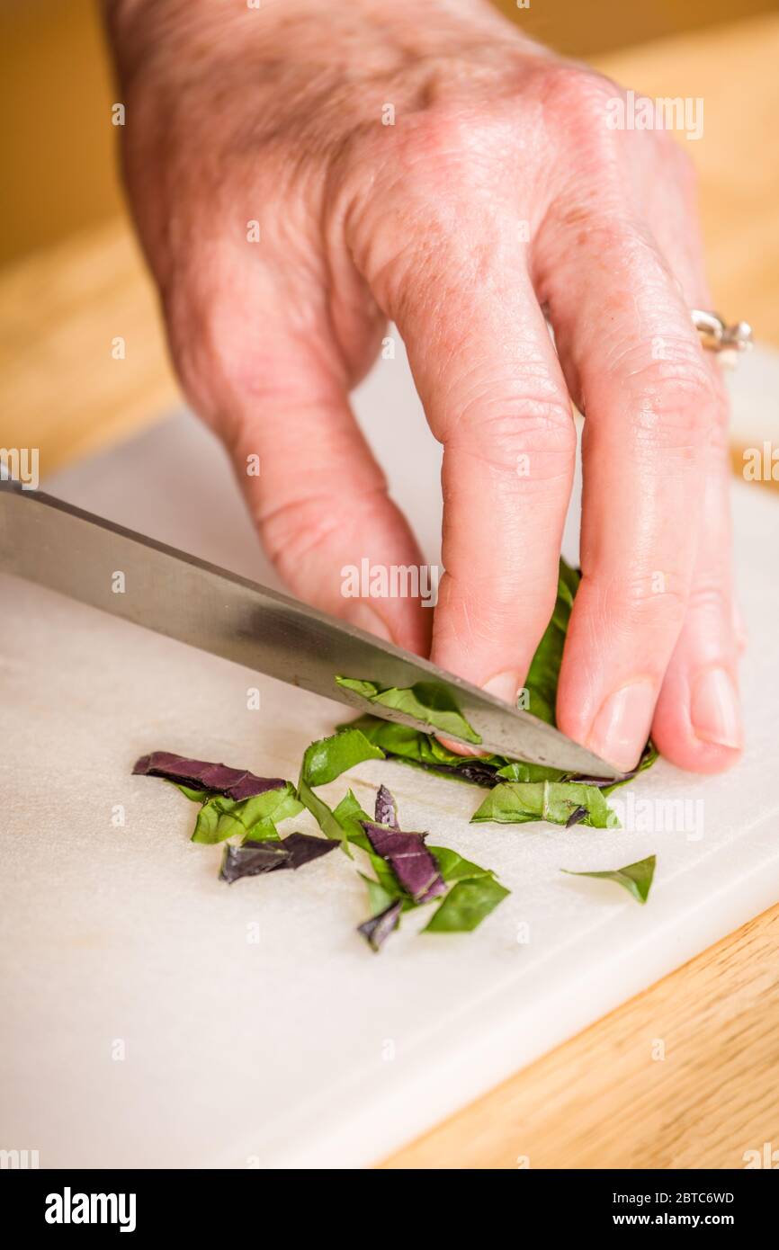 Woman chopping fresh basil using a thin utility knife Stock Photo - Alamy