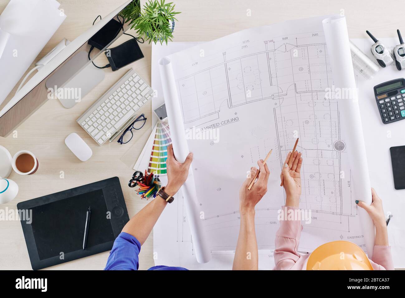 Engineers rolling out blueprint of house and discussing details, view ...