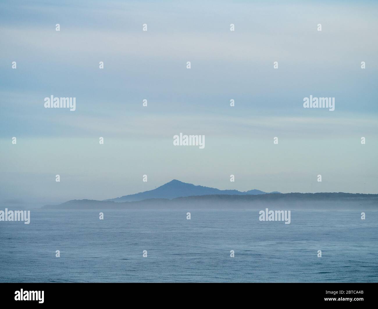 Shades of blue sea, Misty hazy moody seascape, with hills, blue sky and ...