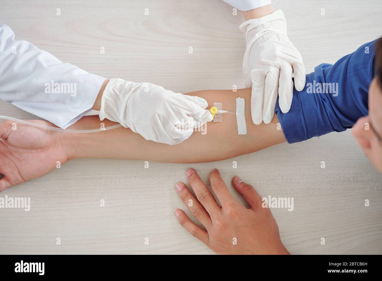 Nurse wearing rubber gloves when adjusting catheter in arm vein of ...