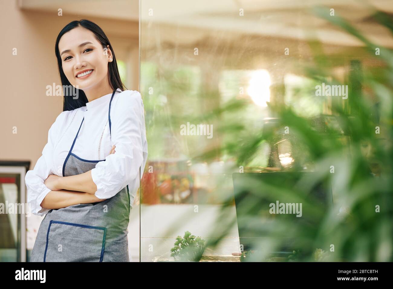 Portrait of smiling pretty young waitress standing at restaurant doors ...