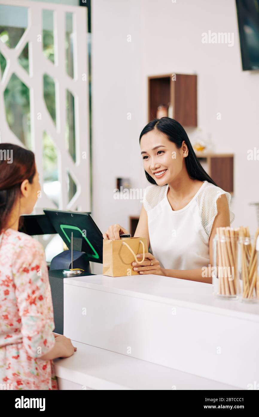 Smiling beautiful Asian shop assistant packing order for client in ...