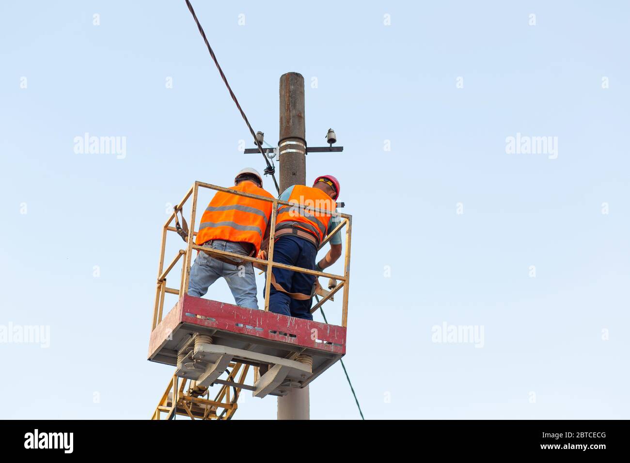 electricians on the pillars install the mount for the power line ...