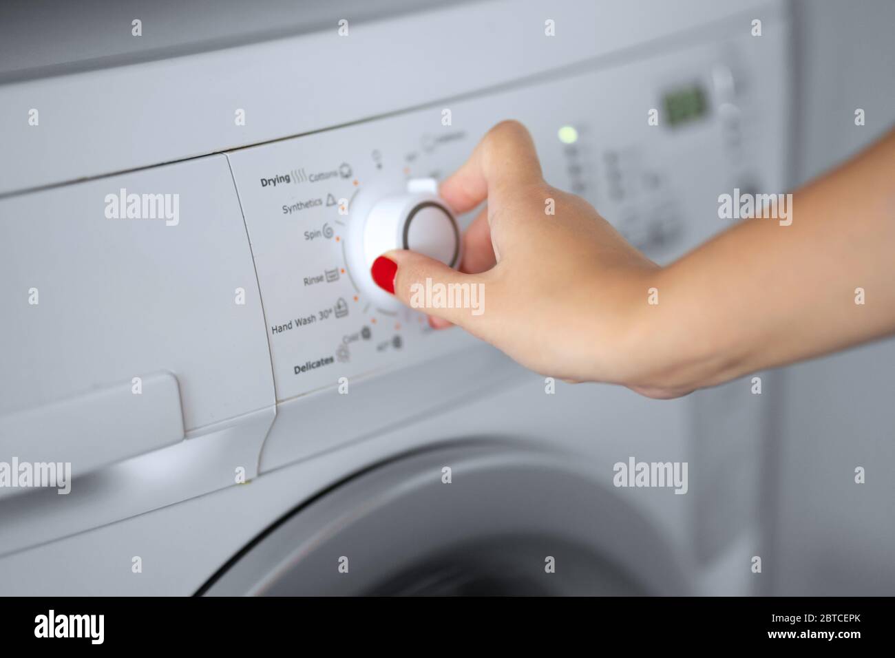 The girl sets the washing program for the washing machine Stock Photo ...