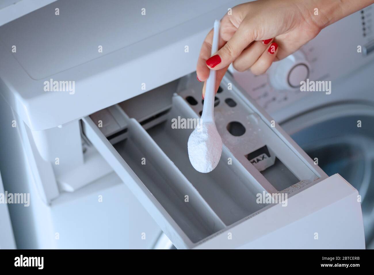 Girl loads detergent into the tray of the washing machine before ...
