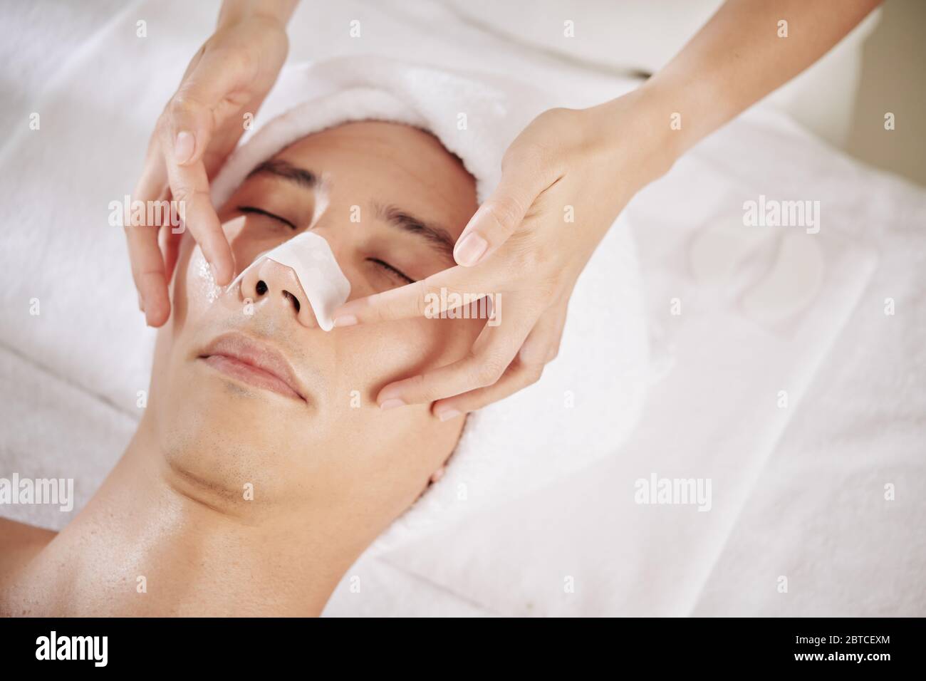 Close-up image of beautician putting sticky nose strip on face of young ...