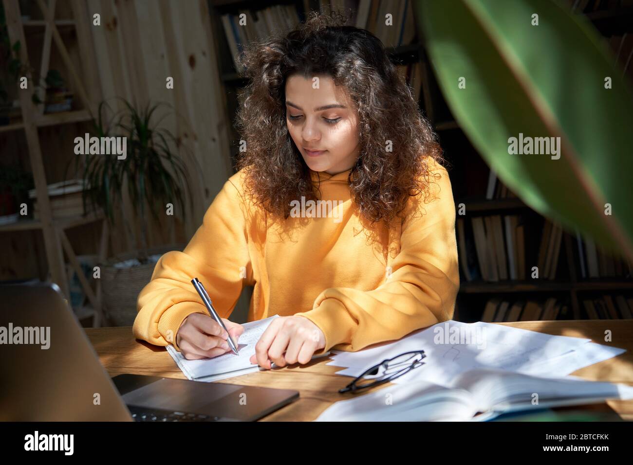 Hispanic teen girl college student studying at home making notes doing ...