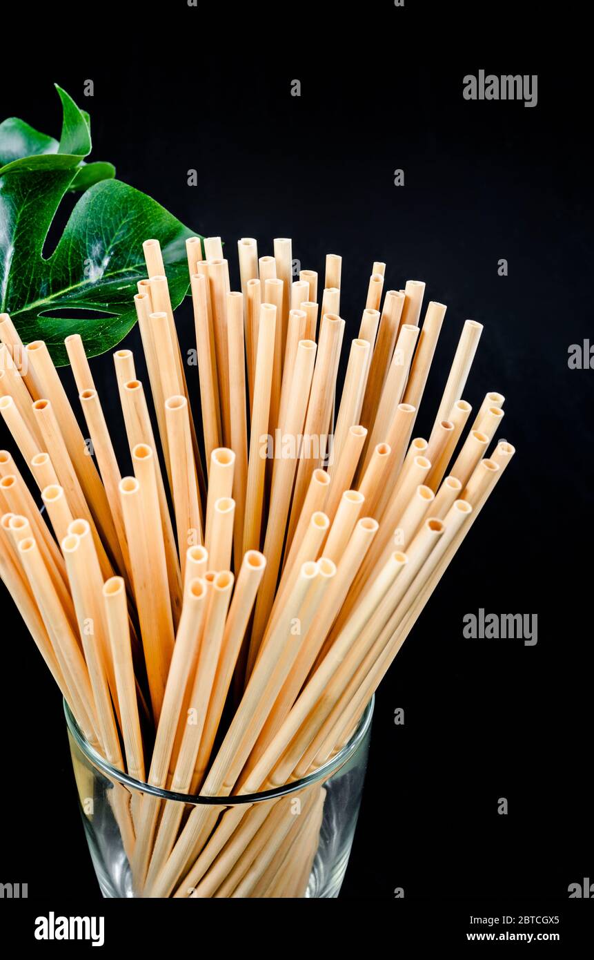 Wheat straw for drinking water in glass with green leaf on black ...