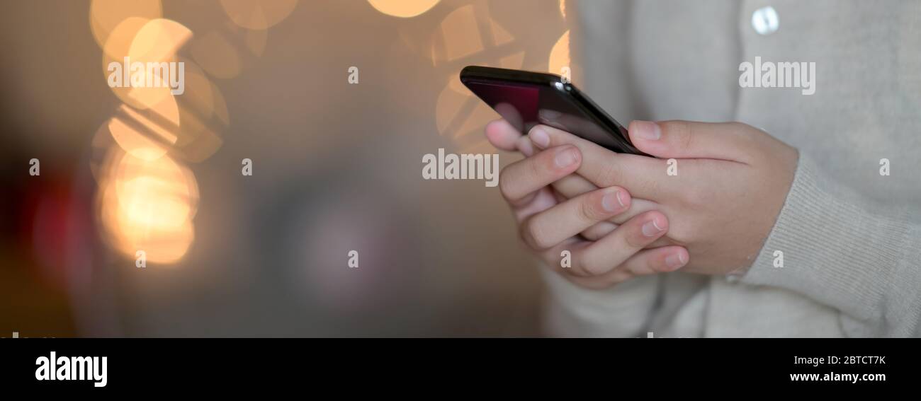 Close up view of a girl holding smartphone while standing with bokeh ...