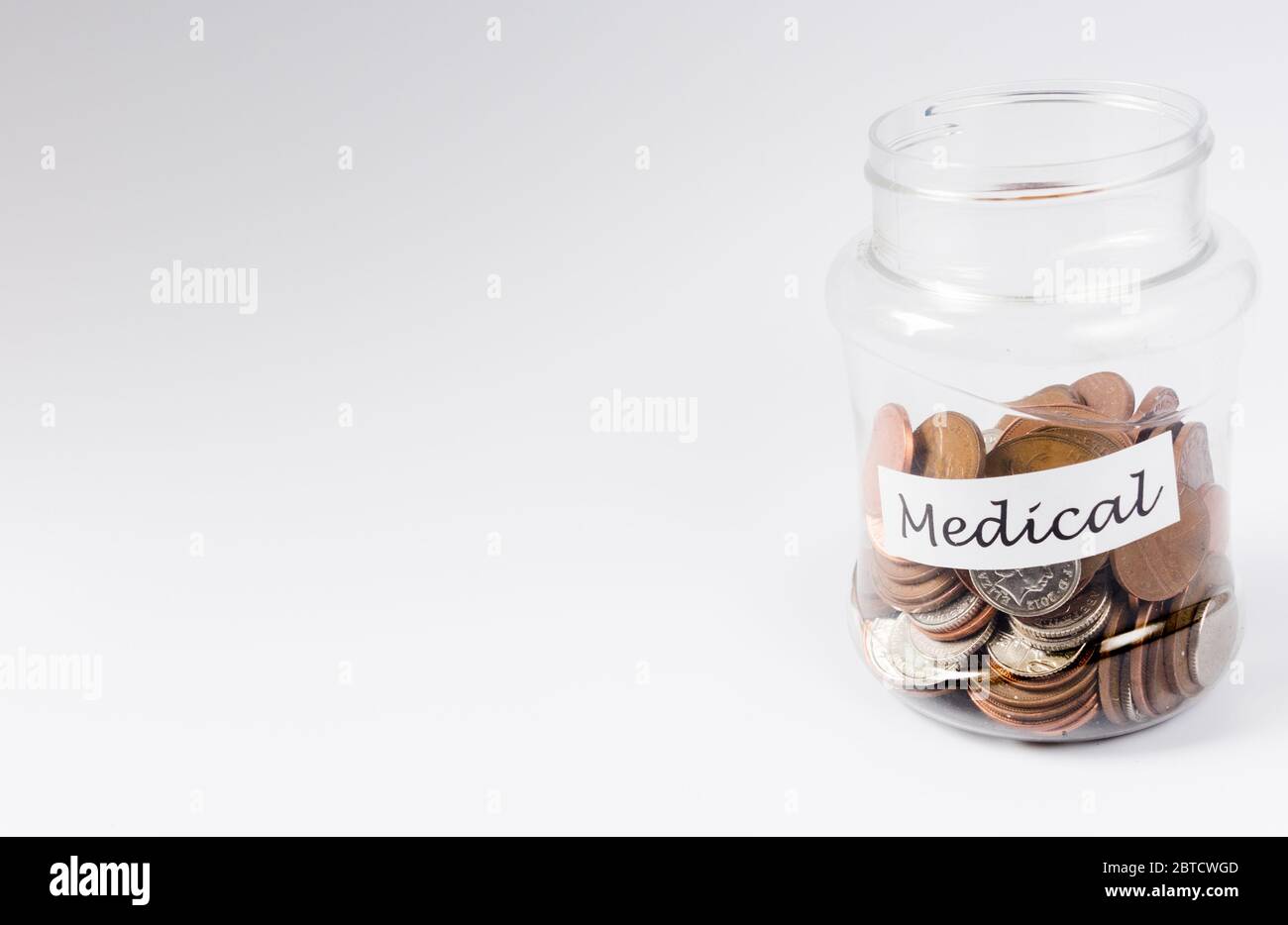 Medical expenses saving pennies in transparent coin jar Stock Photo - Alamy