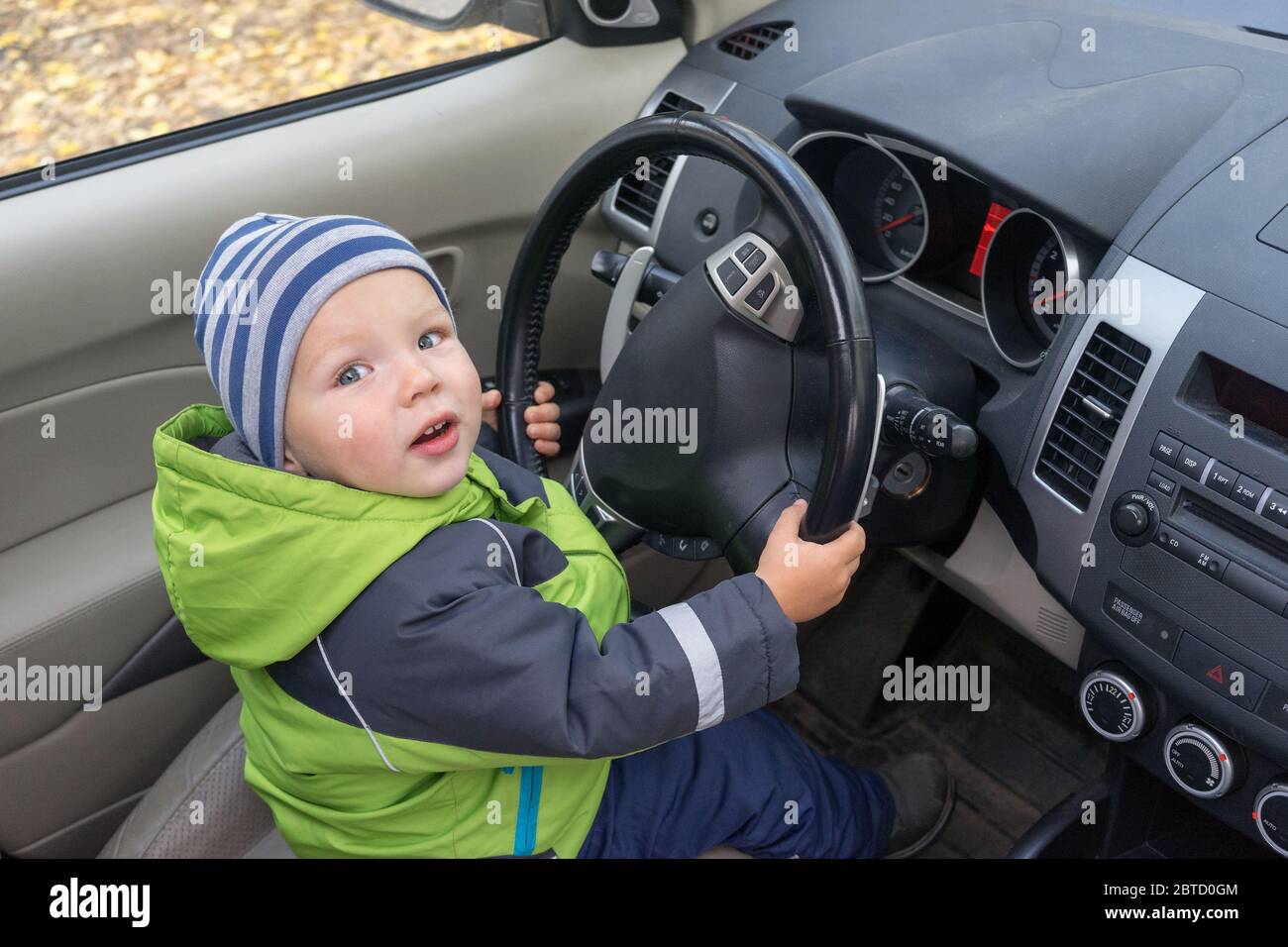 Little boy is sitting at wheel of large car. Imitation of adults ...